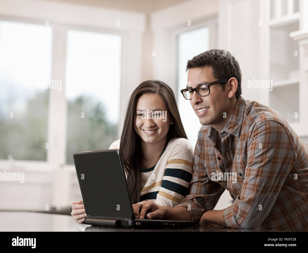 A couple sitting using a laptop computer Stock Photo - Alamy
