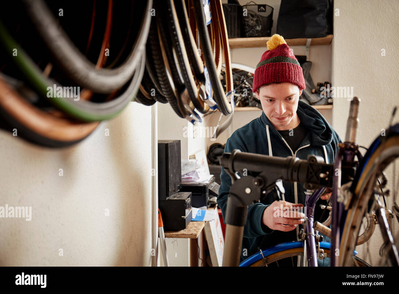A young man working in a cycle shop, repairing a bicycle Stock Photo ...