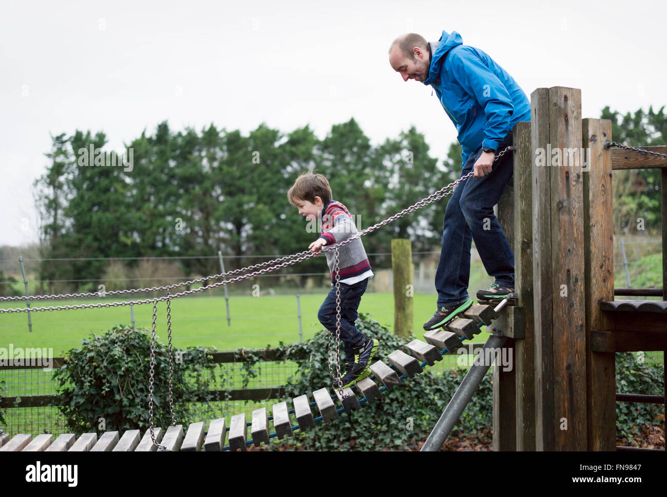 A boy and his father on a climbing frame, balancing on a gangway Stock ...