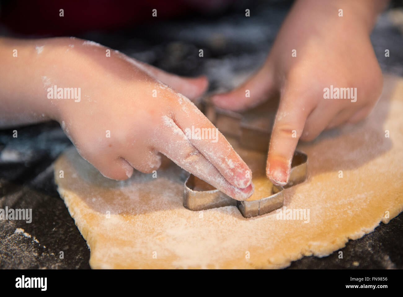 A child using a cookie cutter, making Christmas biscuits Stock Photo ...