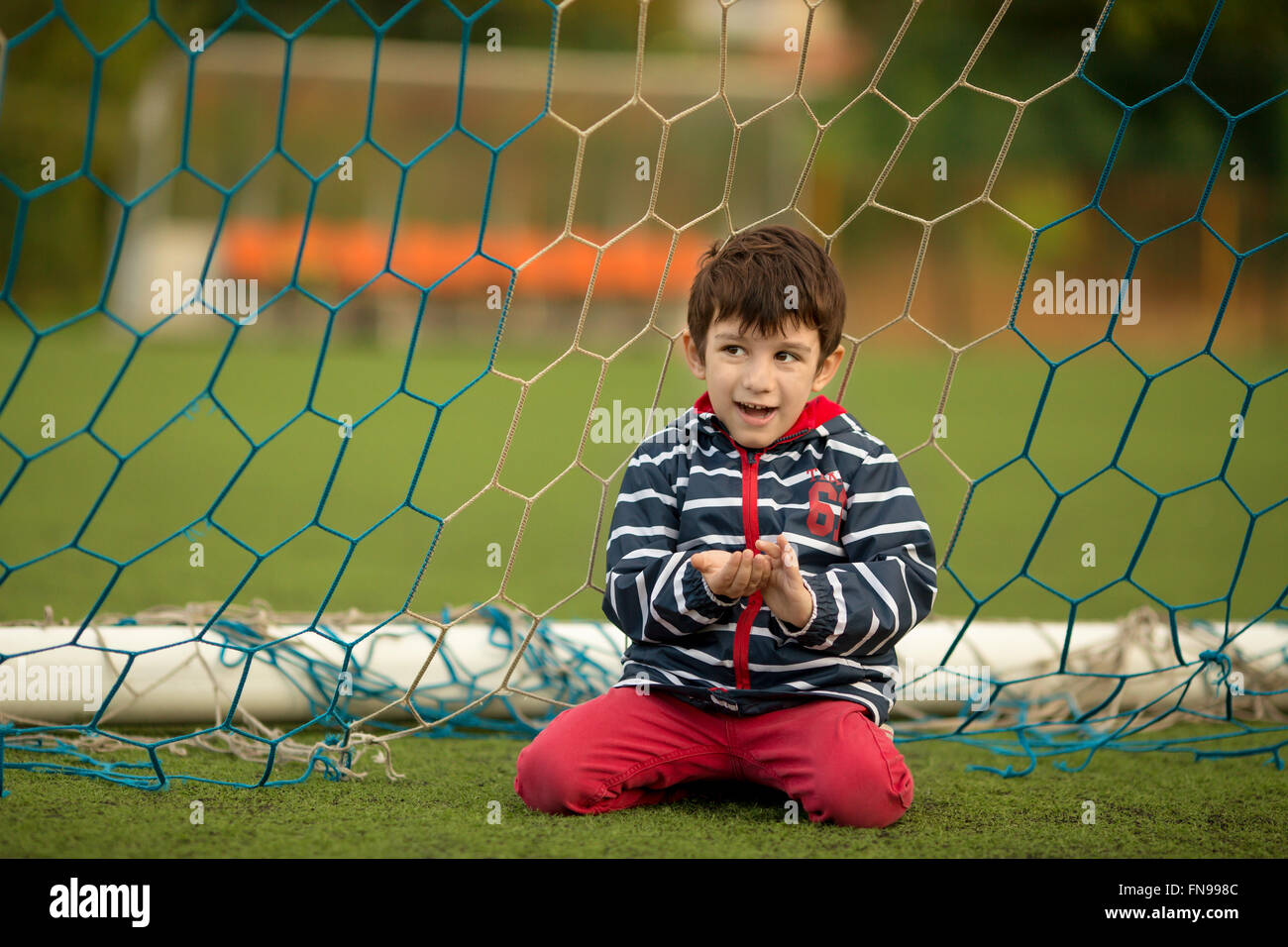 Boy sitting in front of football goal Stock Photo - Alamy