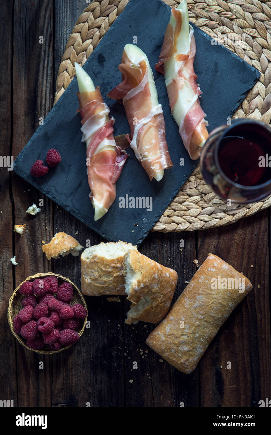 Melon wrapped in parma ham with bread Stock Photo - Alamy