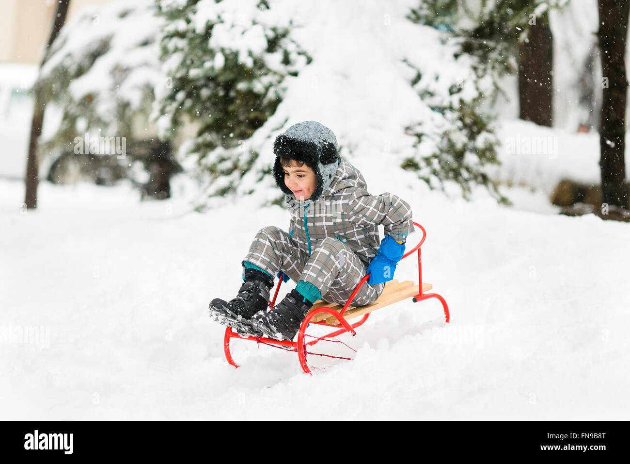 Boy riding sledge in snow Stock Photo - Alamy
