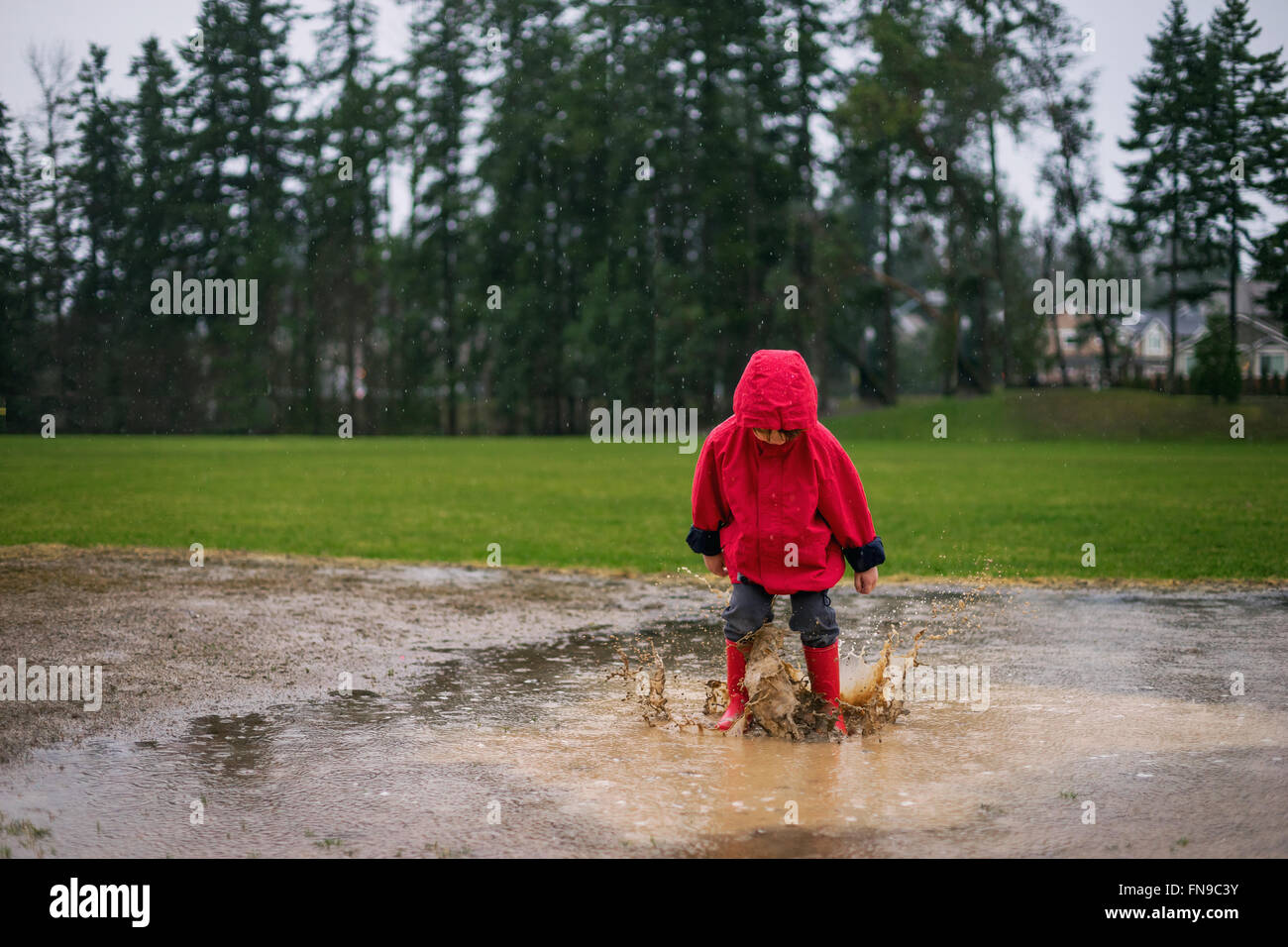 Boy jumping in a puddle in the rain Stock Photo - Alamy