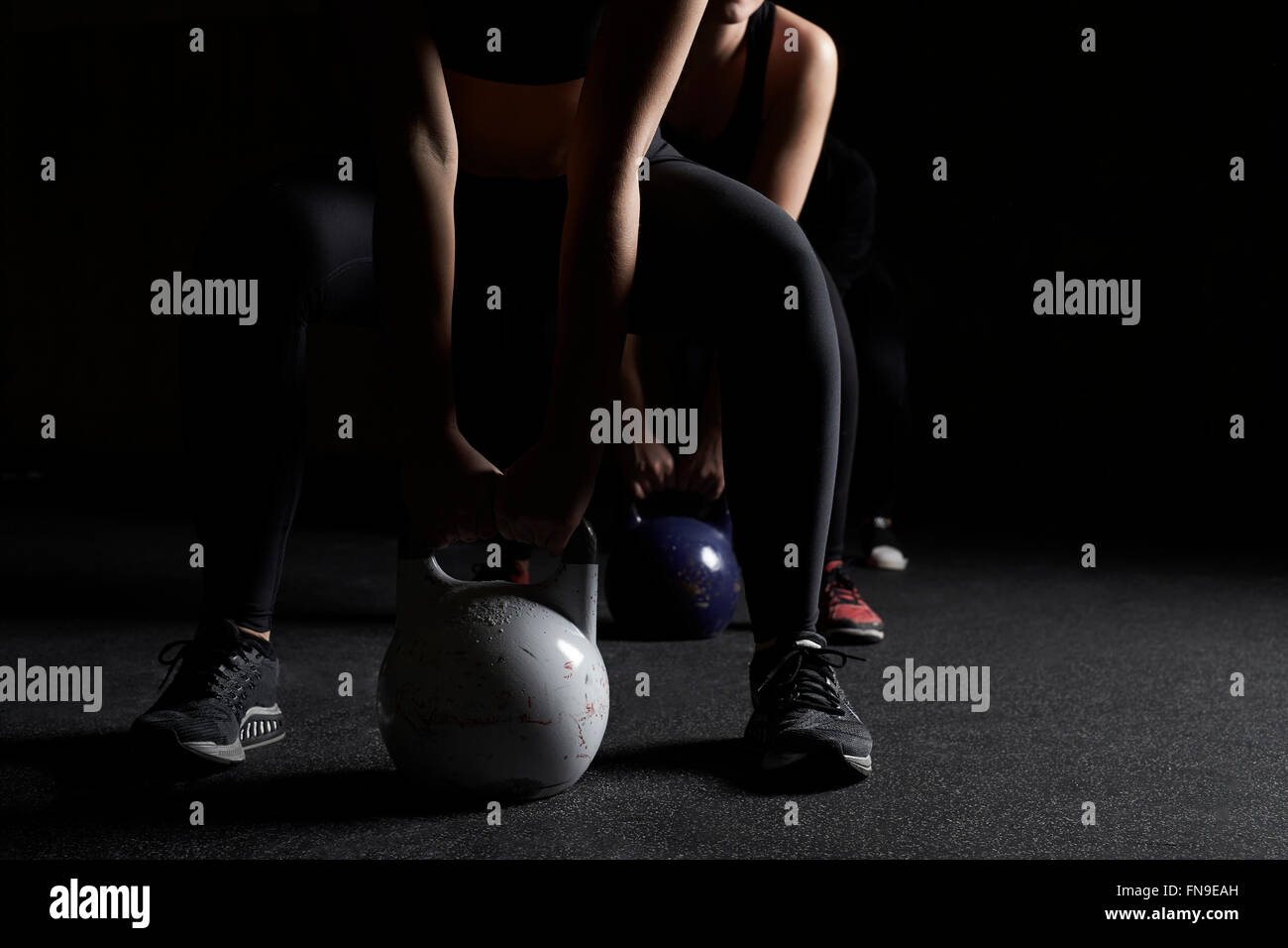 Two women lifting kettle bells in gym Stock Photo - Alamy