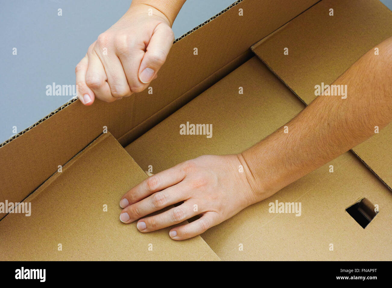 Womans hands opening big cardboard box. Gray background Stock Photo - Alamy