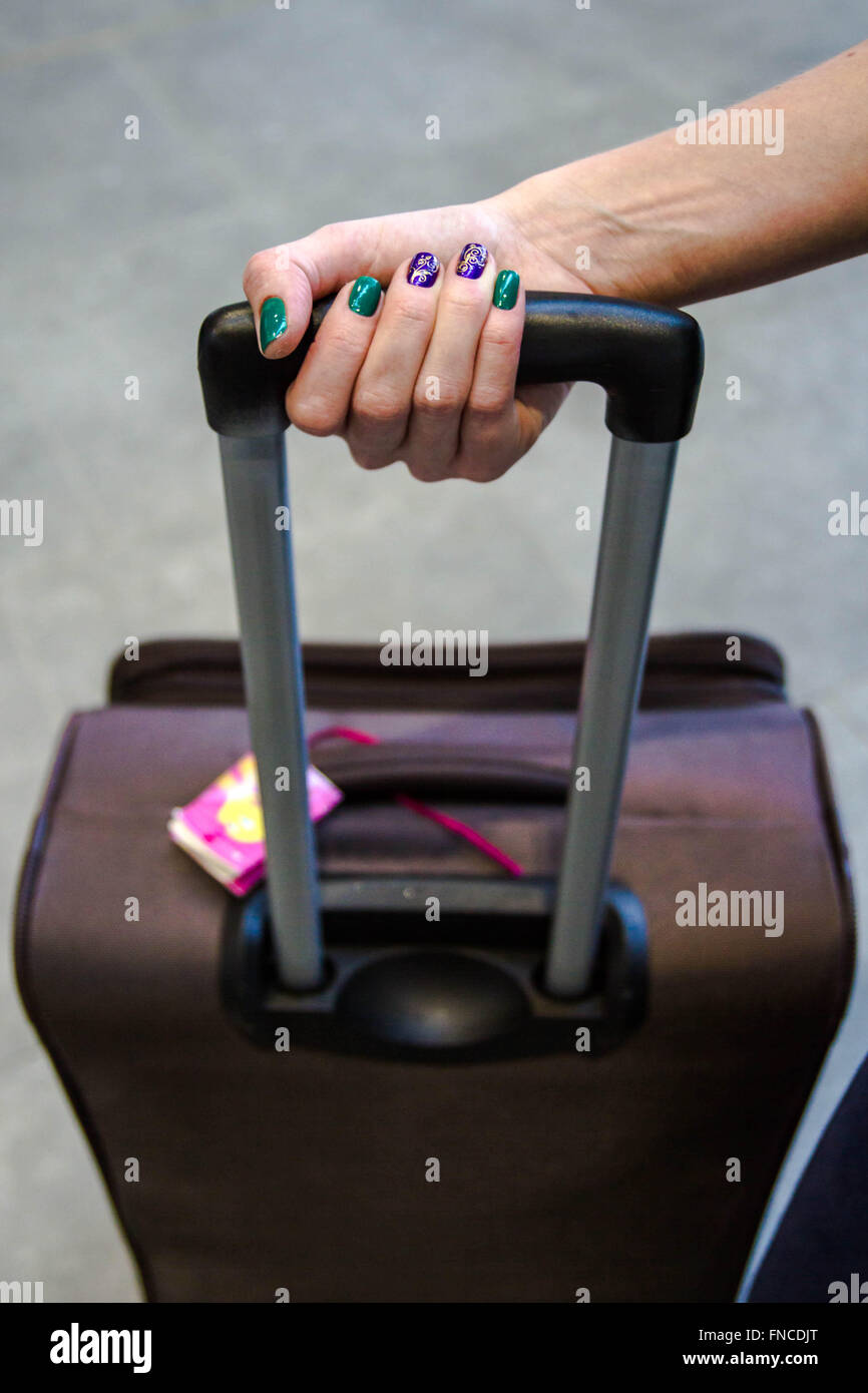 The hand holds the handle of the suitcase Stock Photo - Alamy