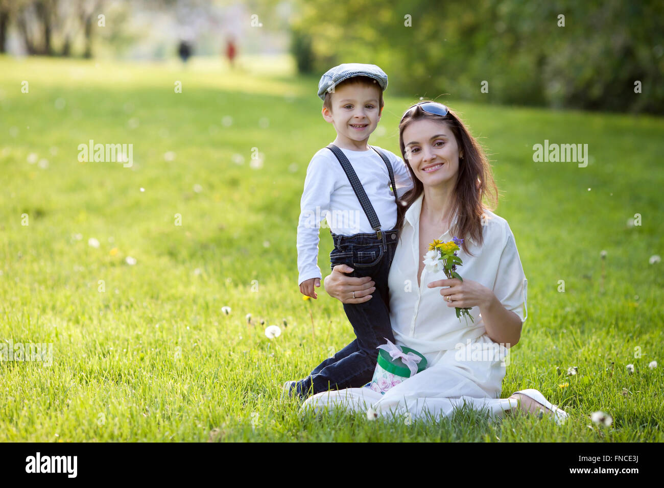 Beautiful kid and mom in spring park, flower and present. Mothers day ...
