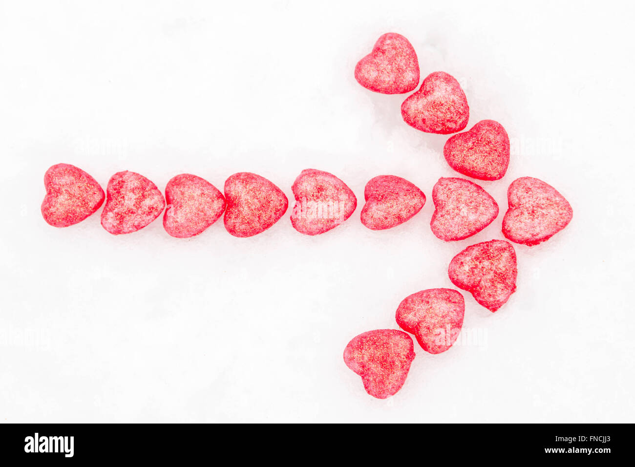 Arrow of pink hearts in the snow Stock Photo - Alamy