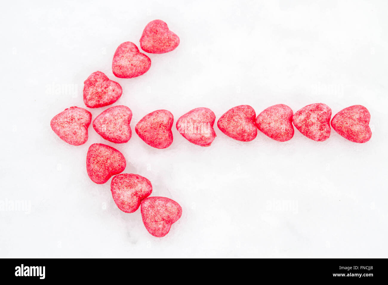 Arrow of pink hearts in the snow Stock Photo - Alamy