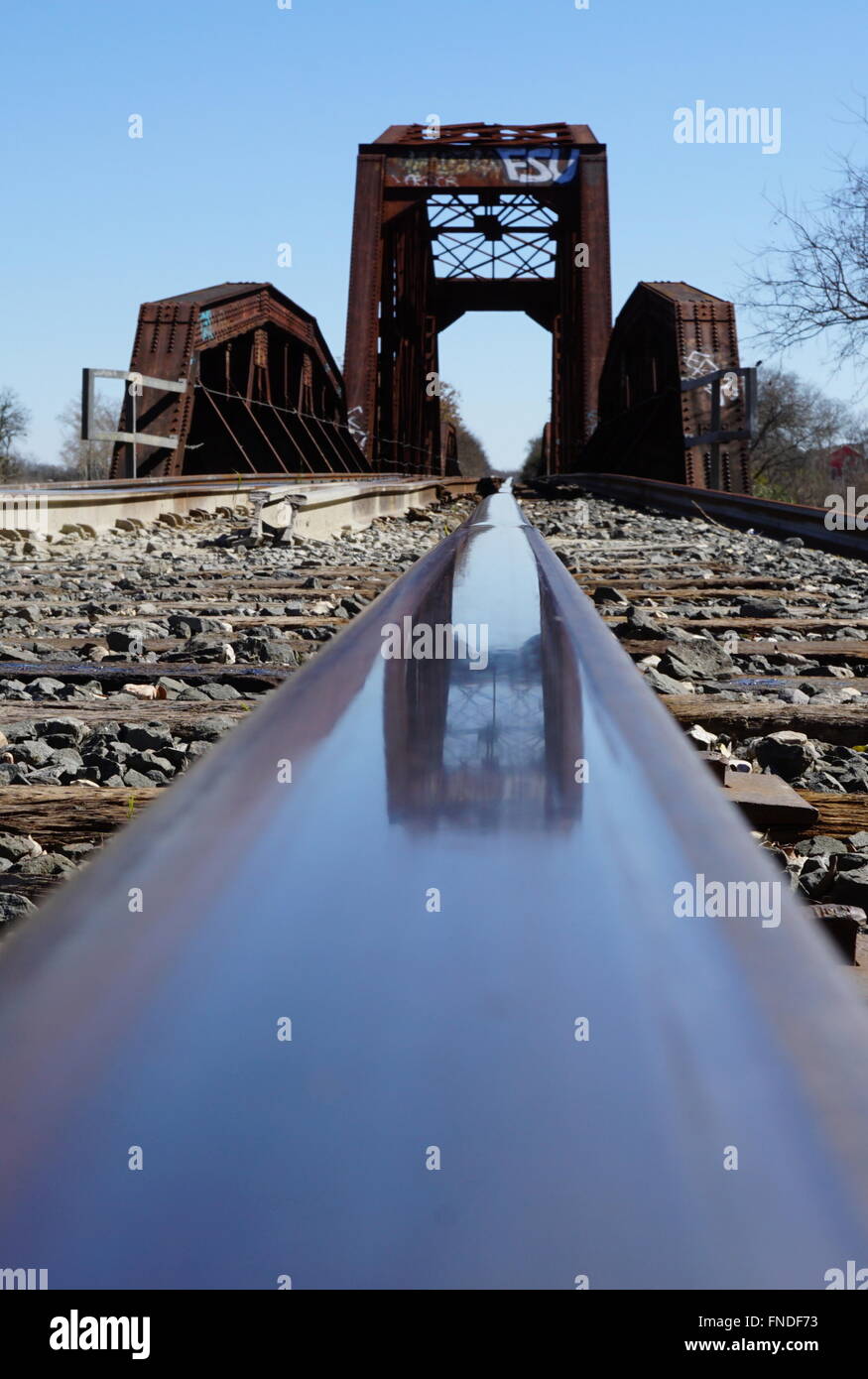 Closeup of a train track reflection the suspension portion of a bridge ...