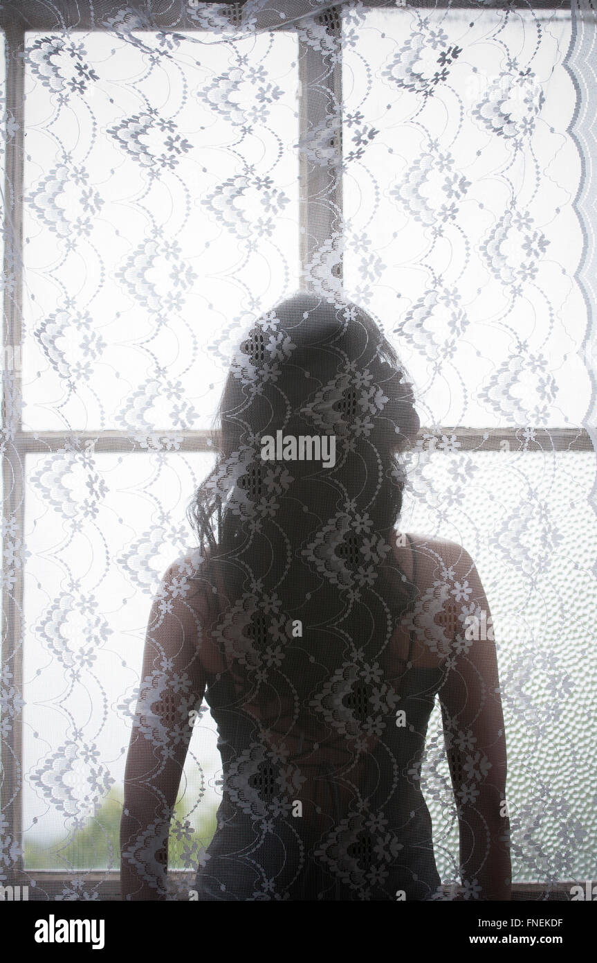 Rear view of a young woman standing by the window Stock Photo - Alamy