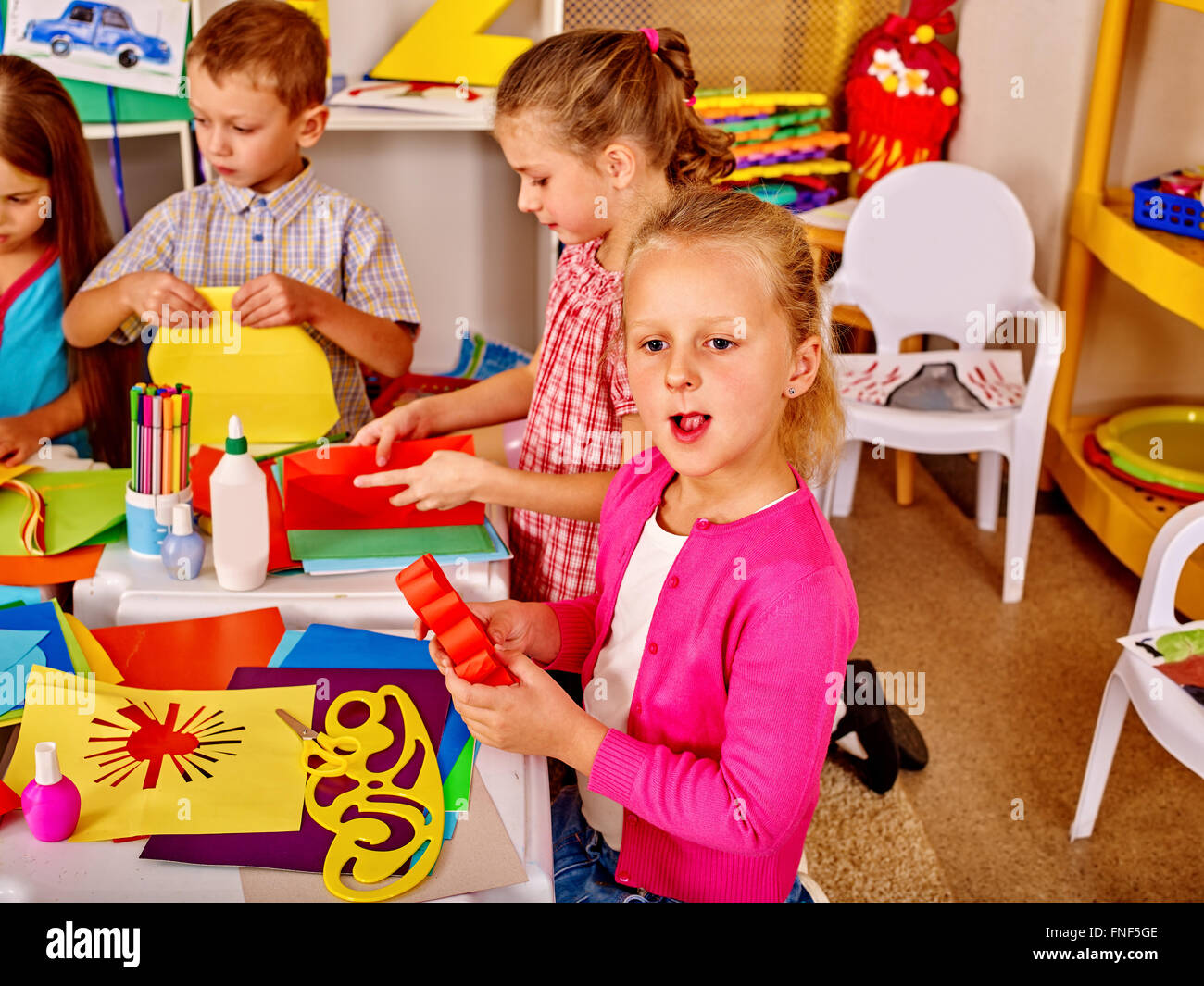 Kids holding colored paper on table in kindergarten Stock Photo - Alamy