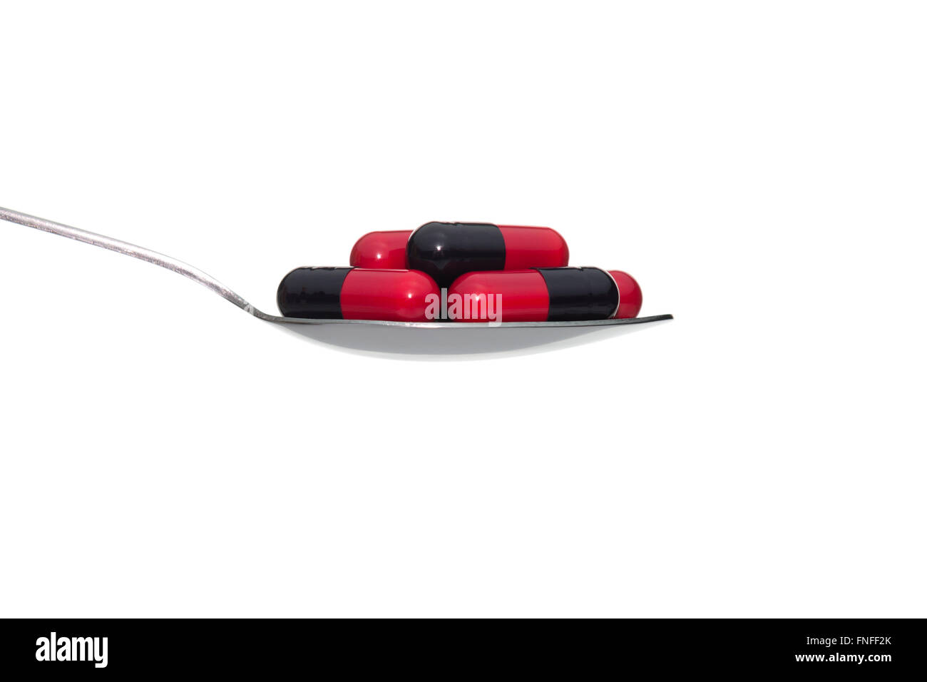 Black red drug or pill or vitamin on metal Spoon isolated on white ...
