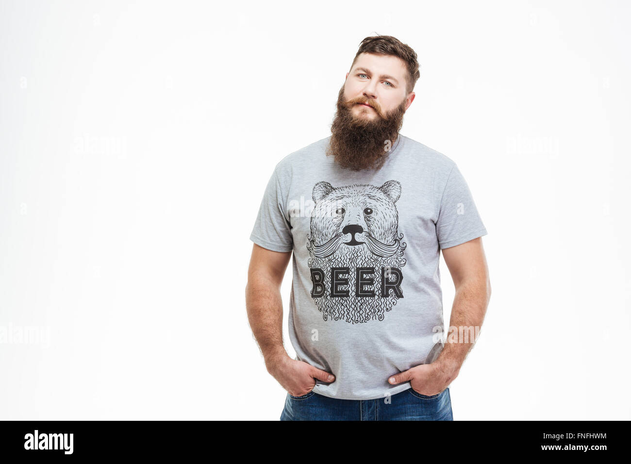 Serious attractive man with beard standing with hands in pockets over ...