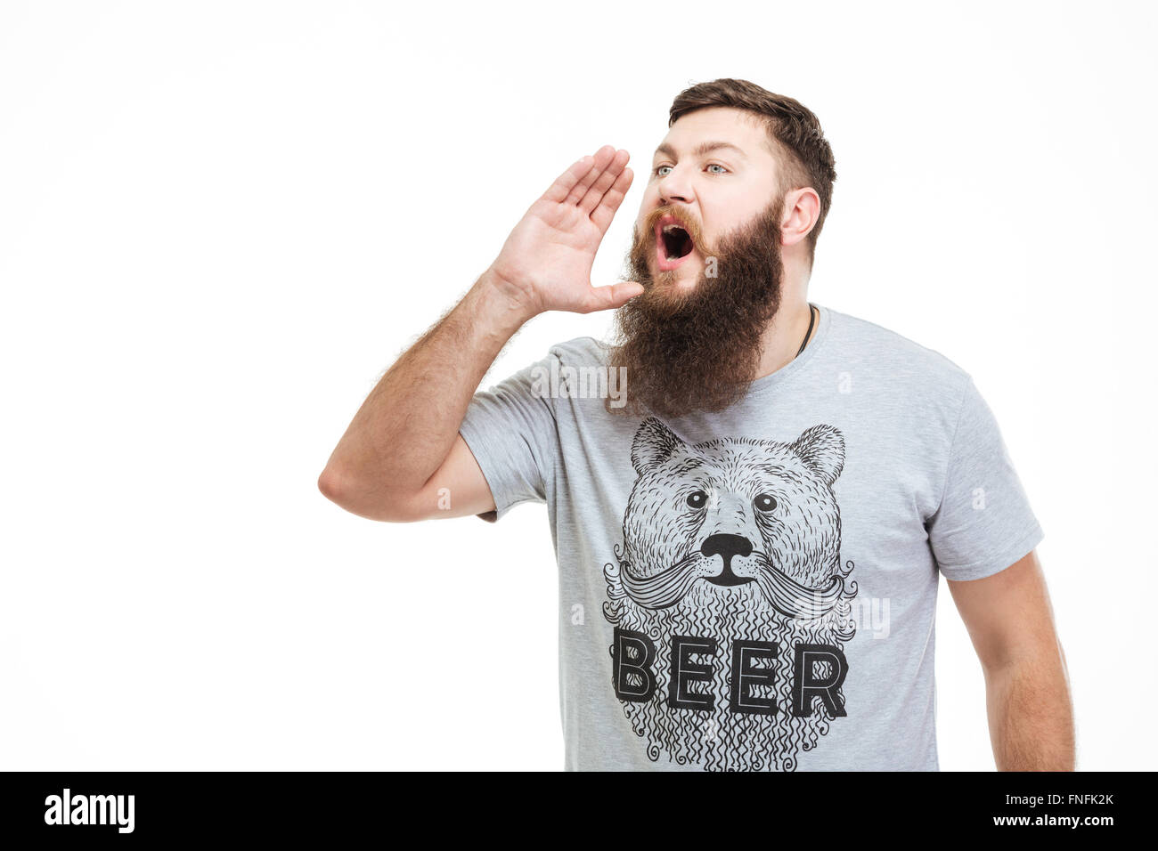 Handsome bearded man shouting loud with hand near mouth over white ...
