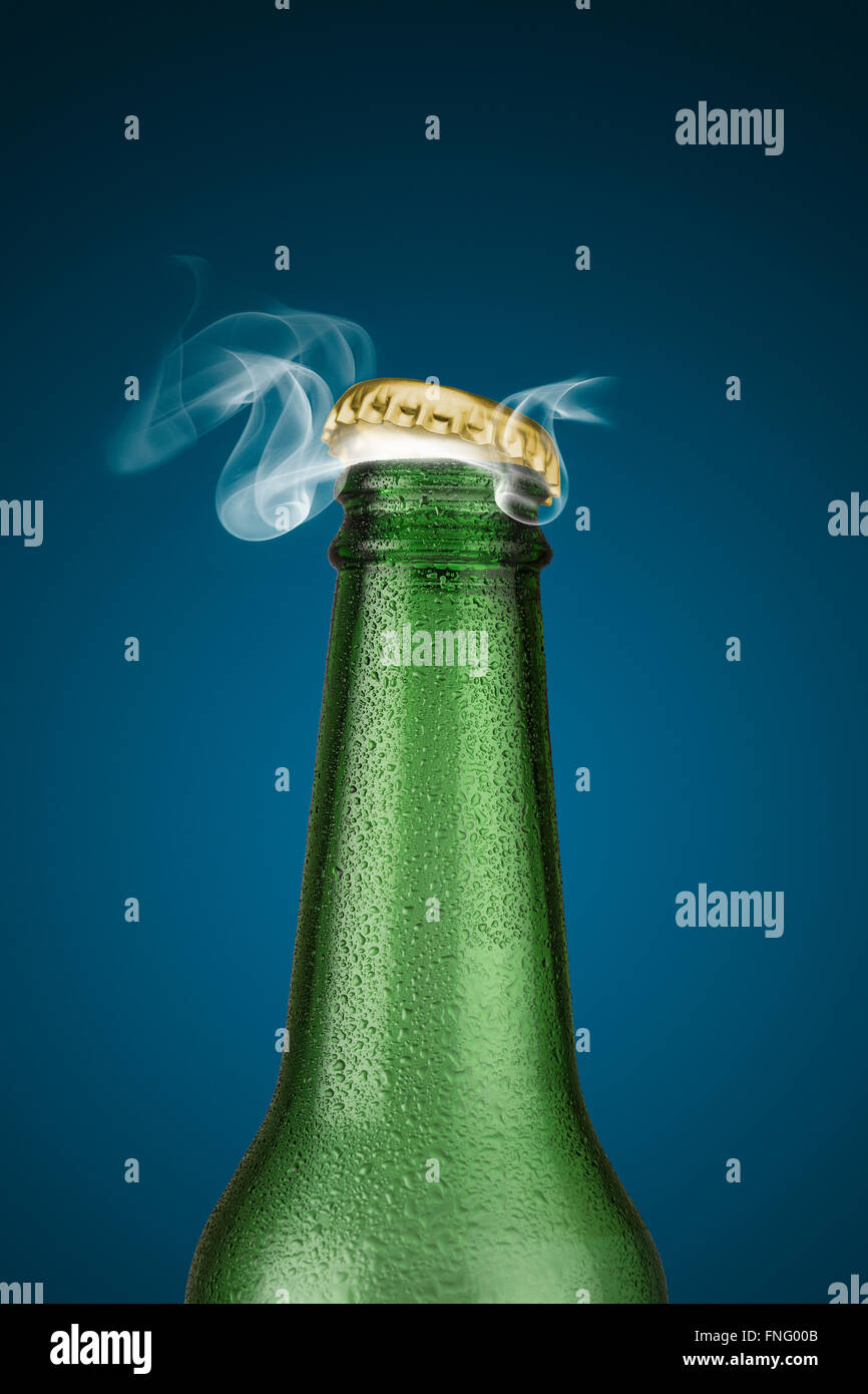 Green cold beer bottle with water drops and golden cap open on blue ...