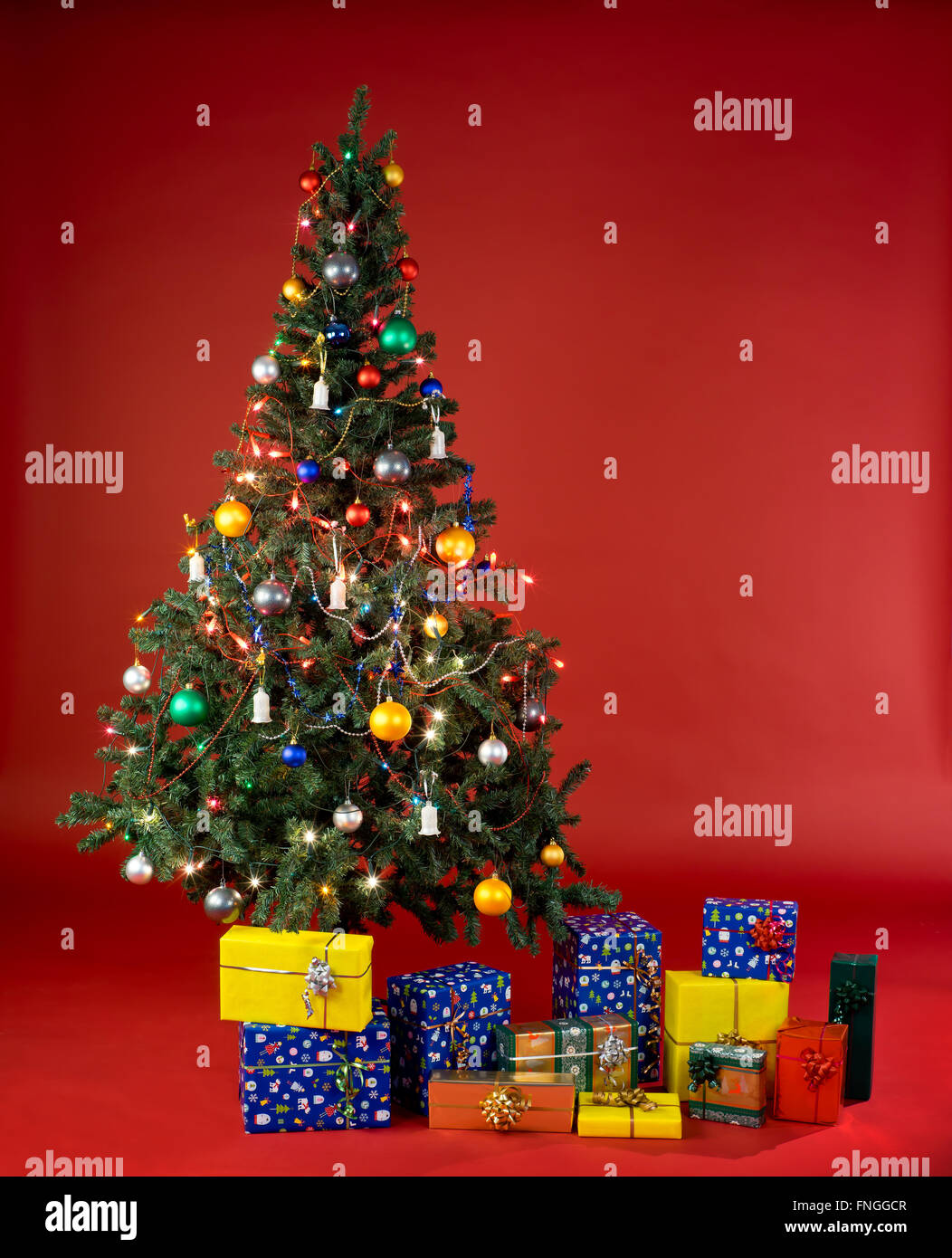 Gifts under the multi color Christmas tree in a red background Stock ...
