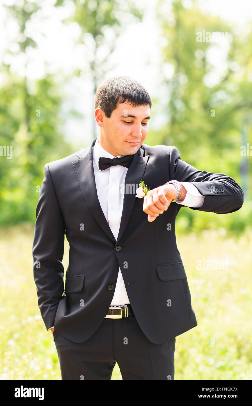 elegant stylish groom waiting his brite and looks at watch Stock Photo ...