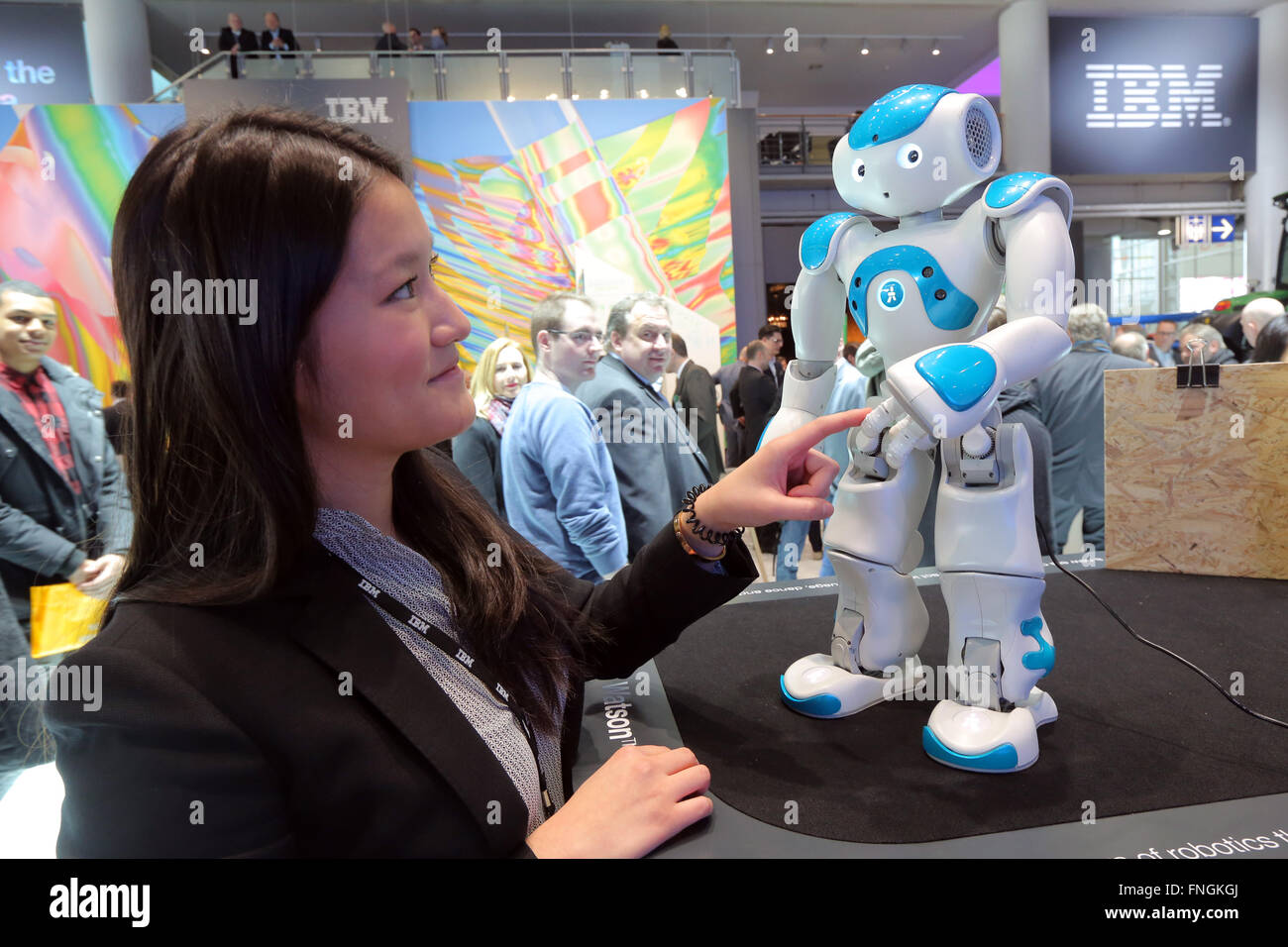 A stand hostess touches a NAO Watson robot at the IBM stand at the 2016 ...