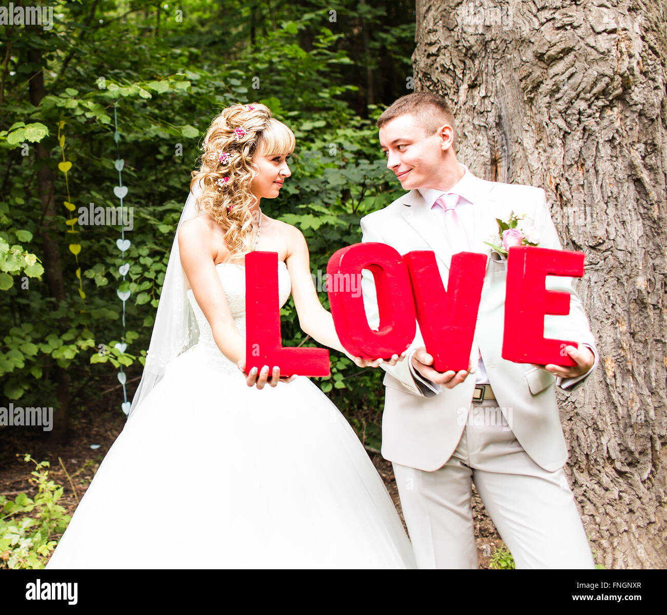 Bride and groom holding the letter word love Stock Photo - Alamy