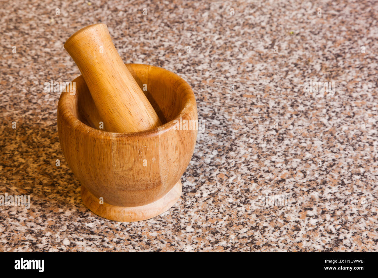 A traditional wooden mortar and pestle on a granite kitchen worktop ...