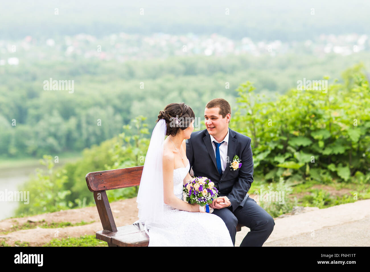 attractive bride and groom sitting on a bench Stock Photo - Alamy