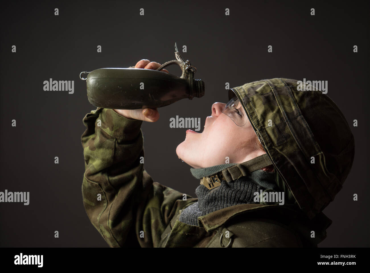 Thirsty soldier and last water droplets. Portrait of female soldier who ...