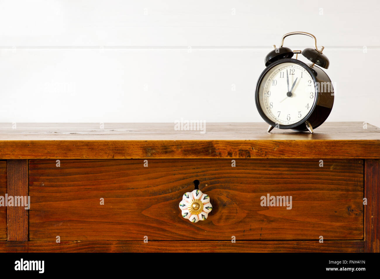 Retro alarm clock on bedside table, background white wooden wall Stock ...