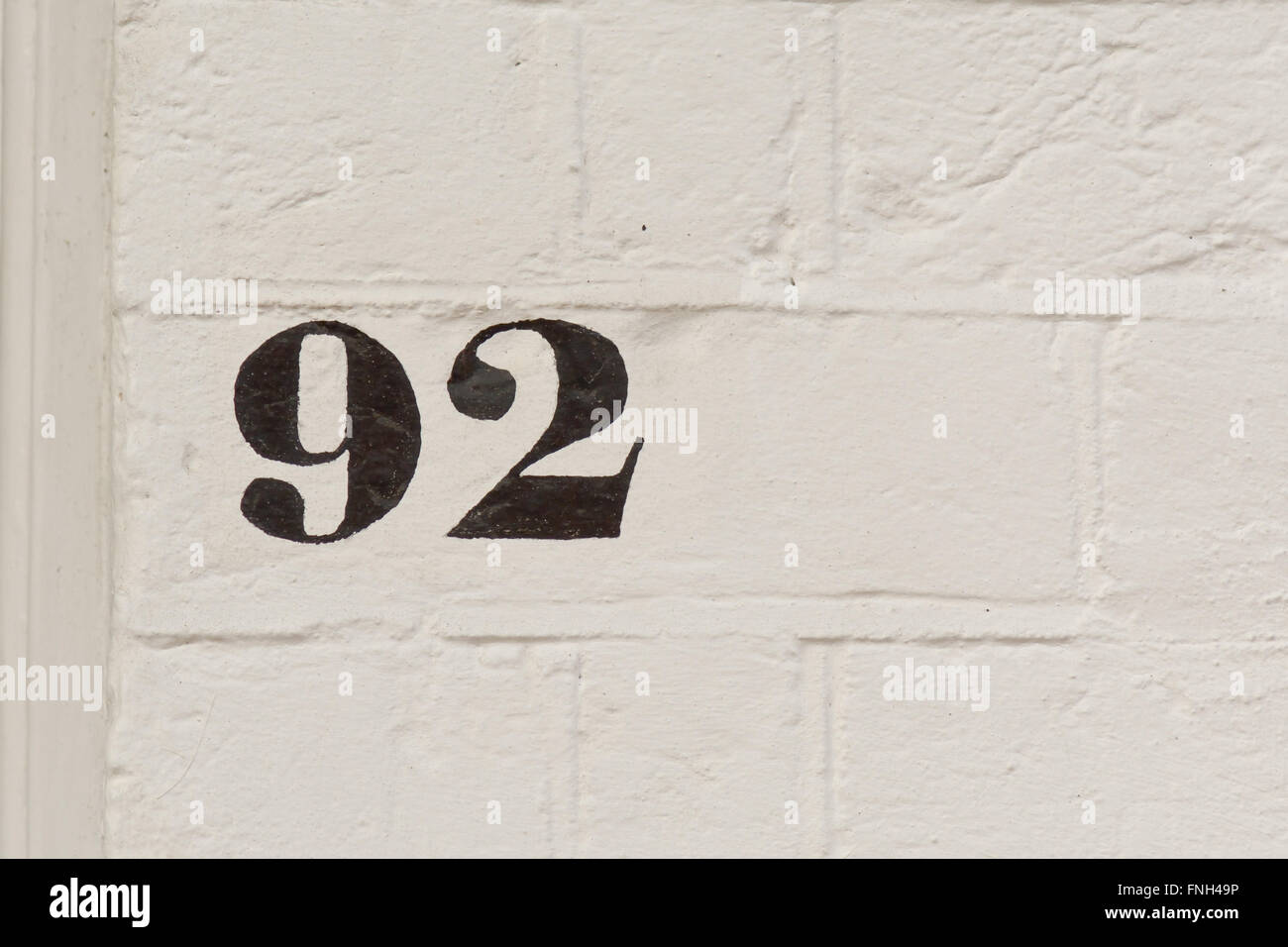 House number 92 painted sign - black on white wall Stock Photo - Alamy