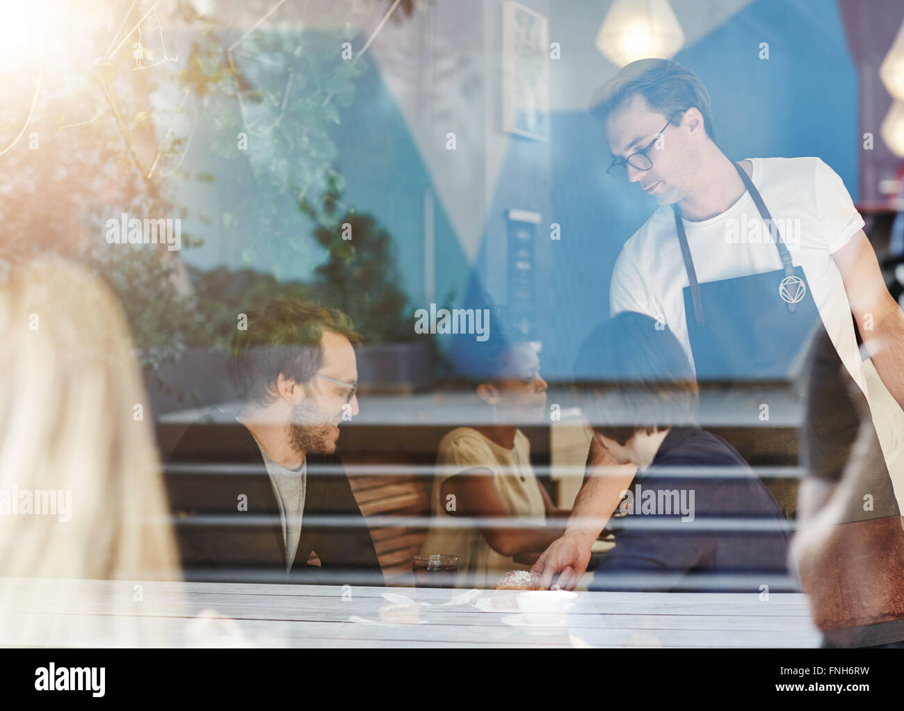 Couple being served by a waiter in busy cafe Stock Photo - Alamy