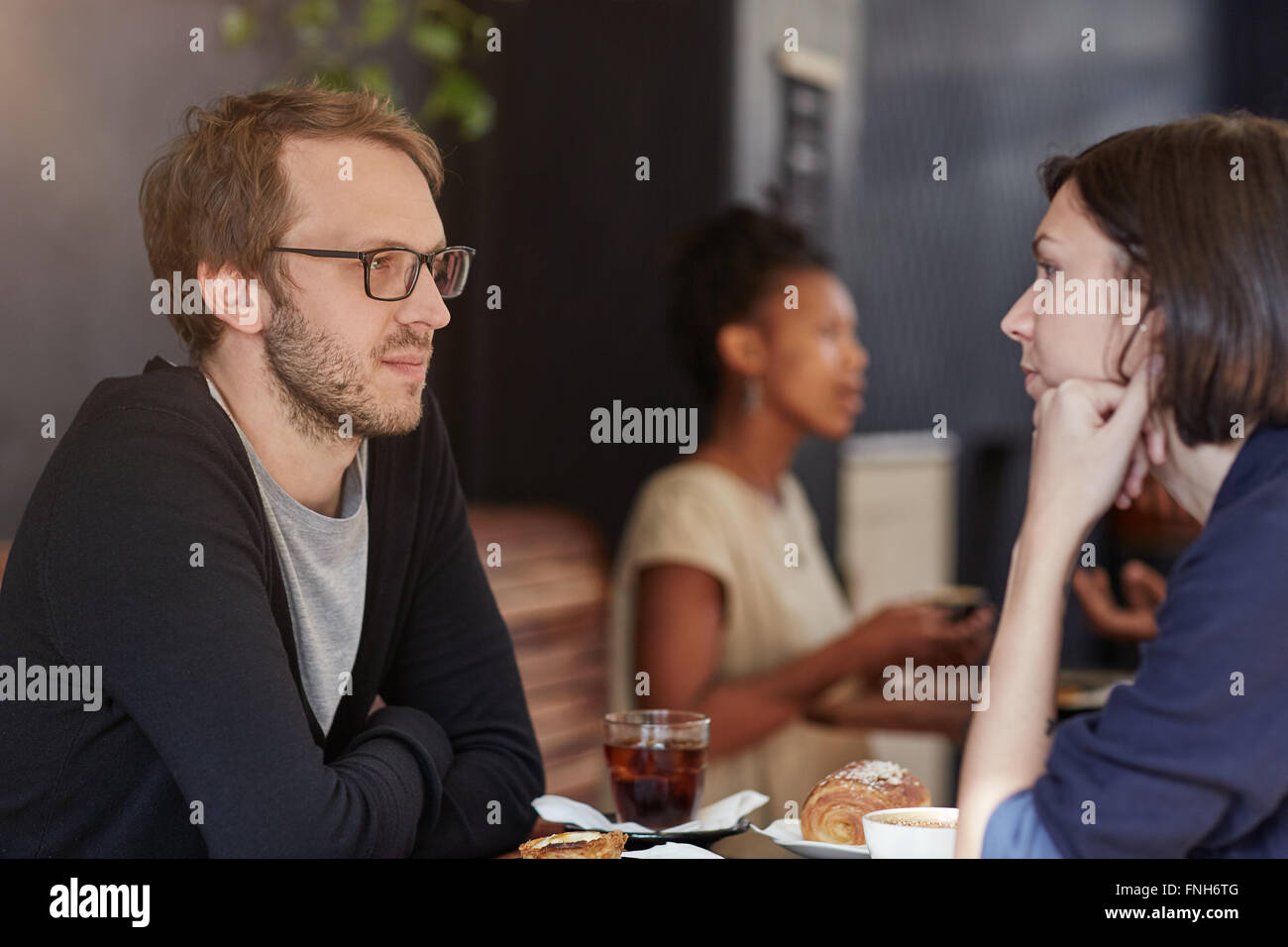 Man looking serious at a cafe table with female companion Stock Photo ...