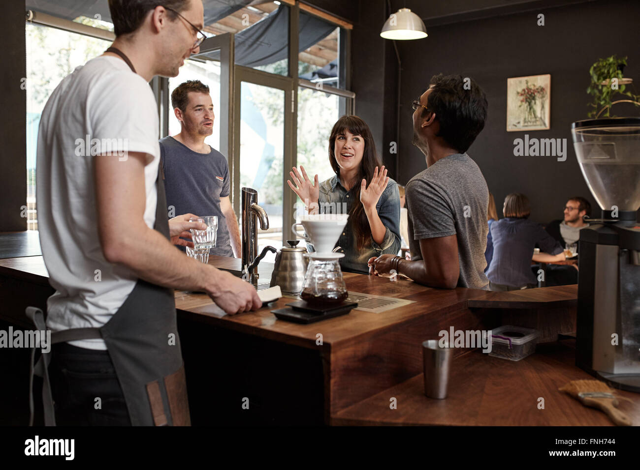 Woman gesturing while talking with colleagues at coffee shop Stock ...