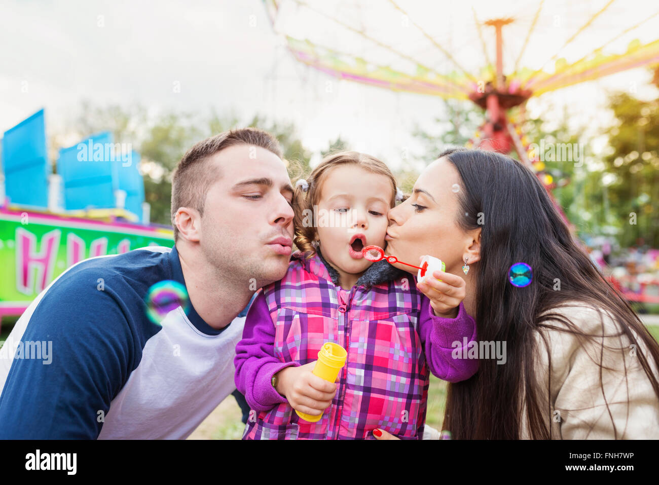 Father, mother and daughter blowing bubbles, family in amusement Stock ...