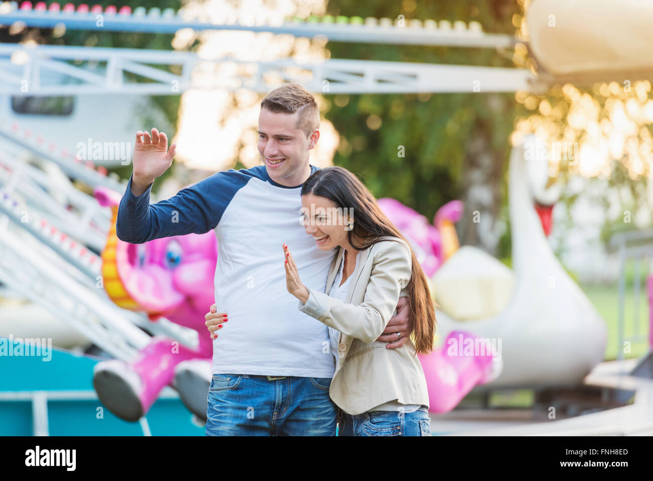 Parents at fun fair, waving their child taking ride Stock Photo - Alamy