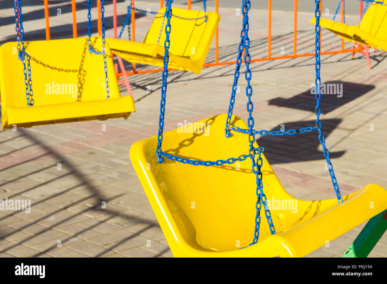 Attraction yellow swing on a chain Stock Photo - Alamy
