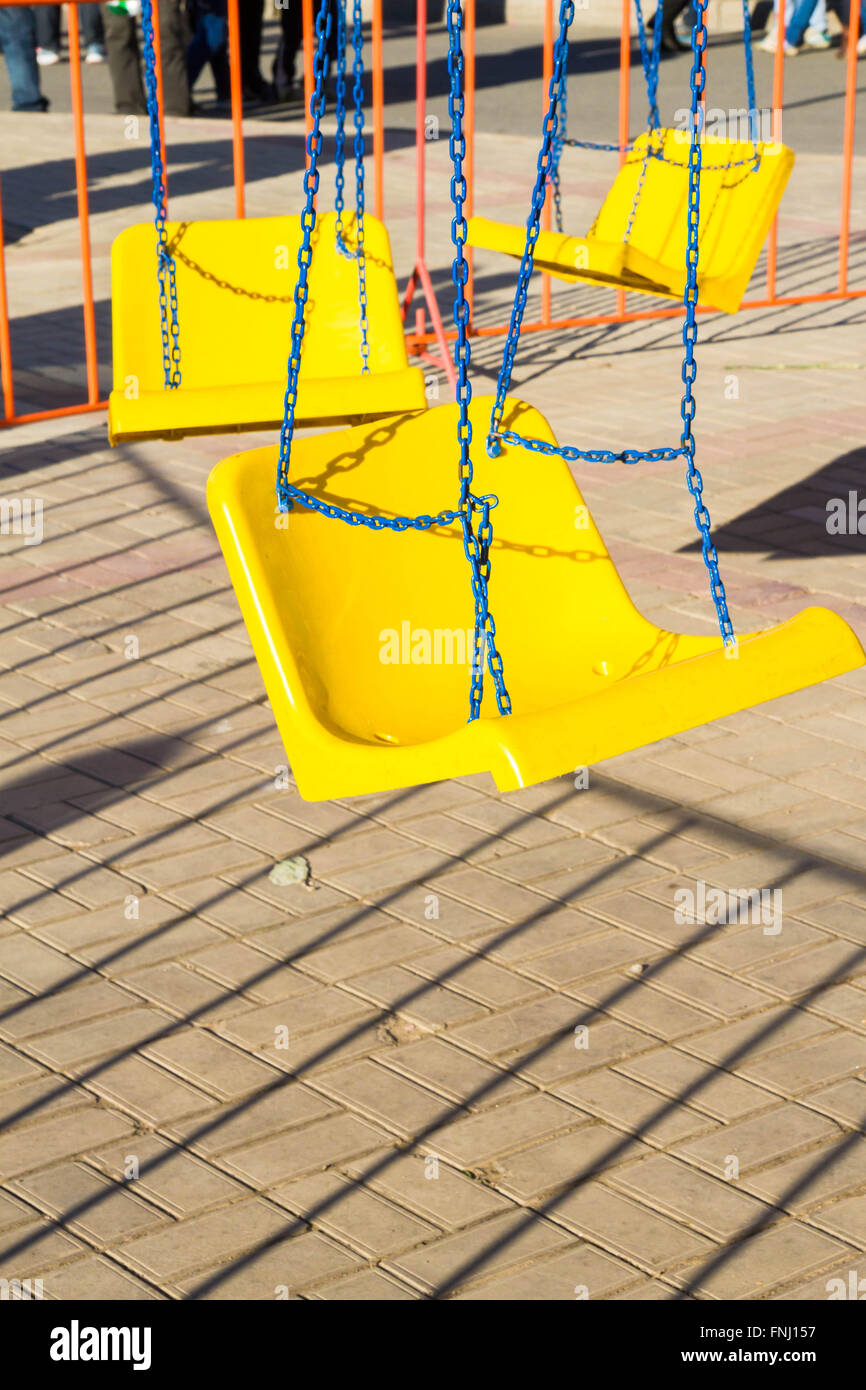 Attraction yellow swing on a chain Stock Photo - Alamy