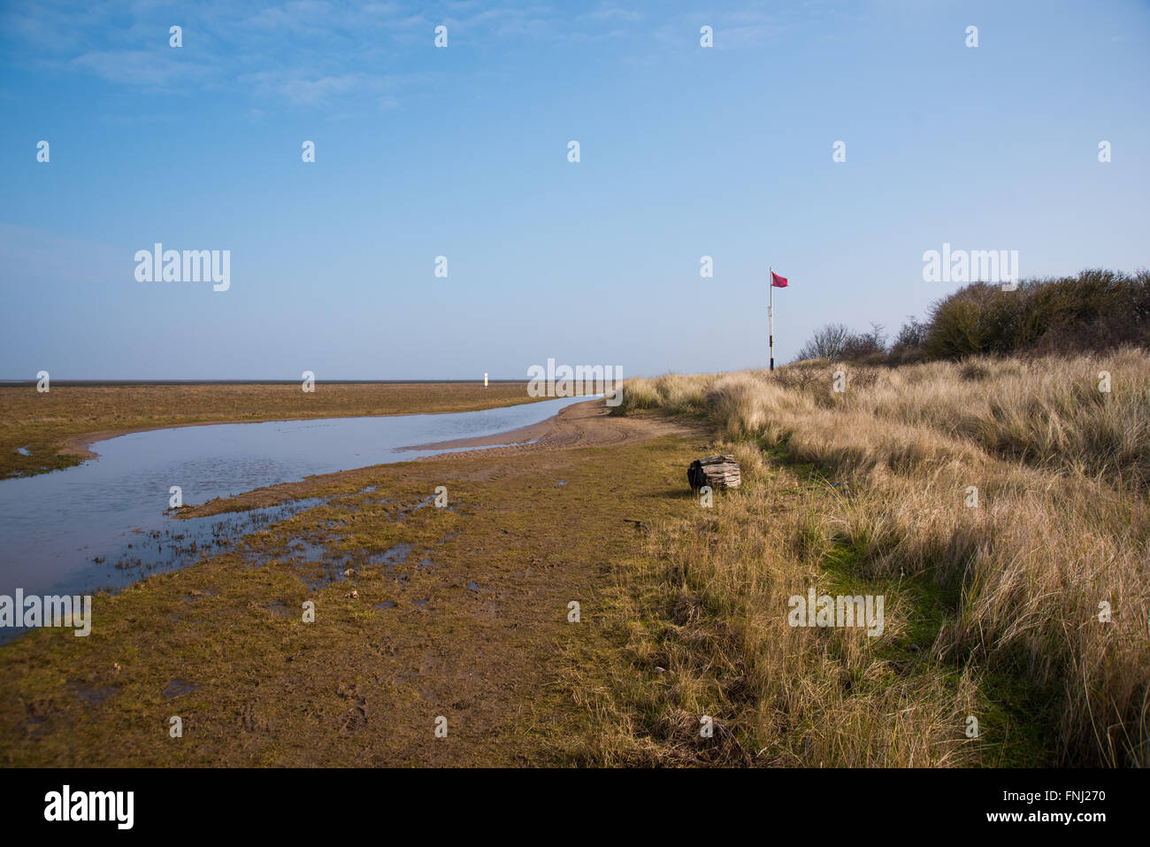 A bombing range warning flag flies next to footpath along the dunes at ...