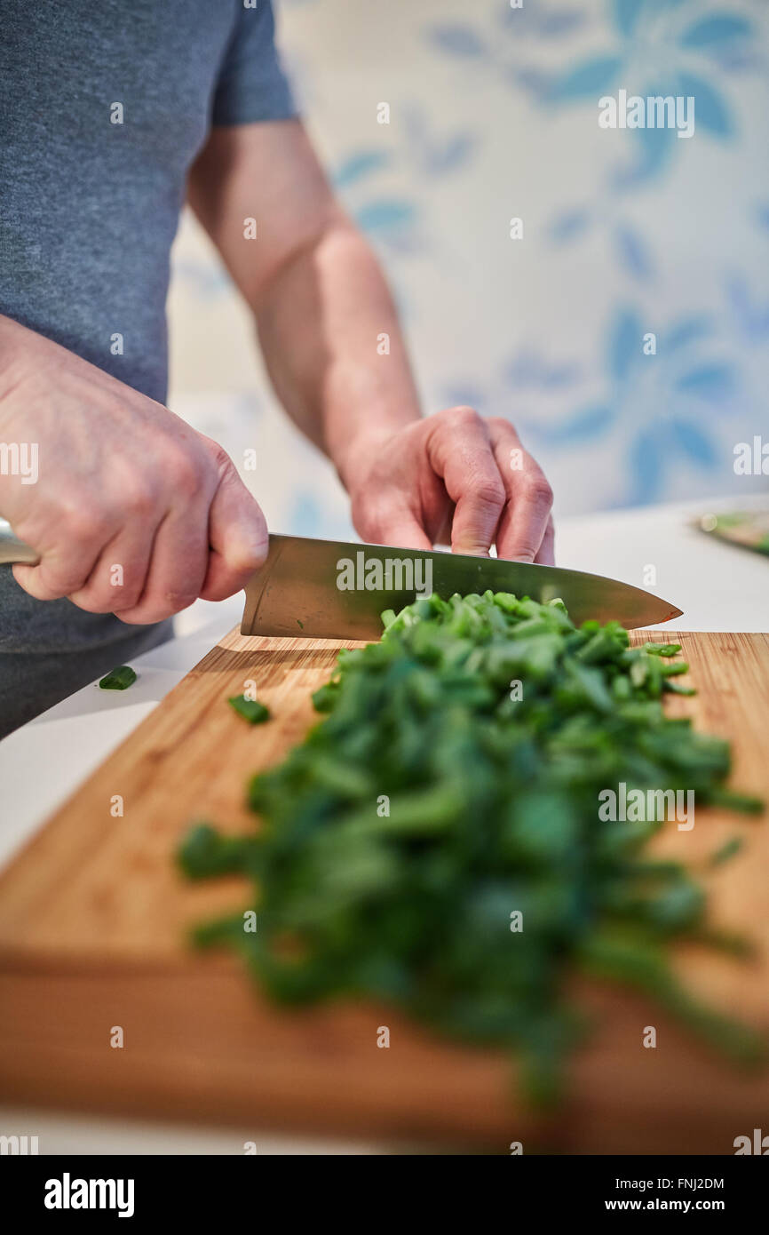 Hands of man chopping spring onions on a wooden board for a salad Stock ...