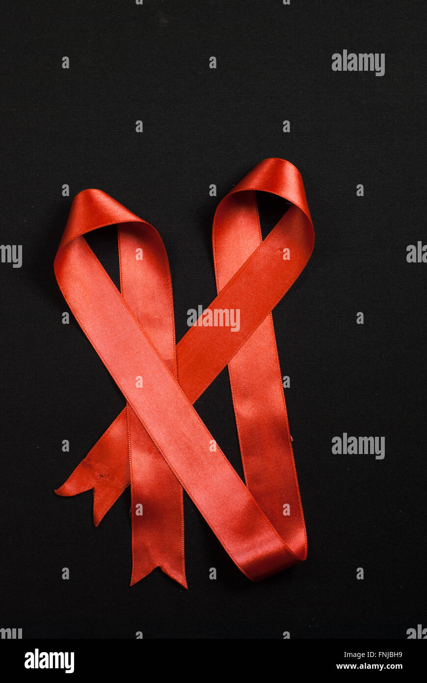 Red ribbon HIV, AIDS isolated on black Stock Photo - Alamy