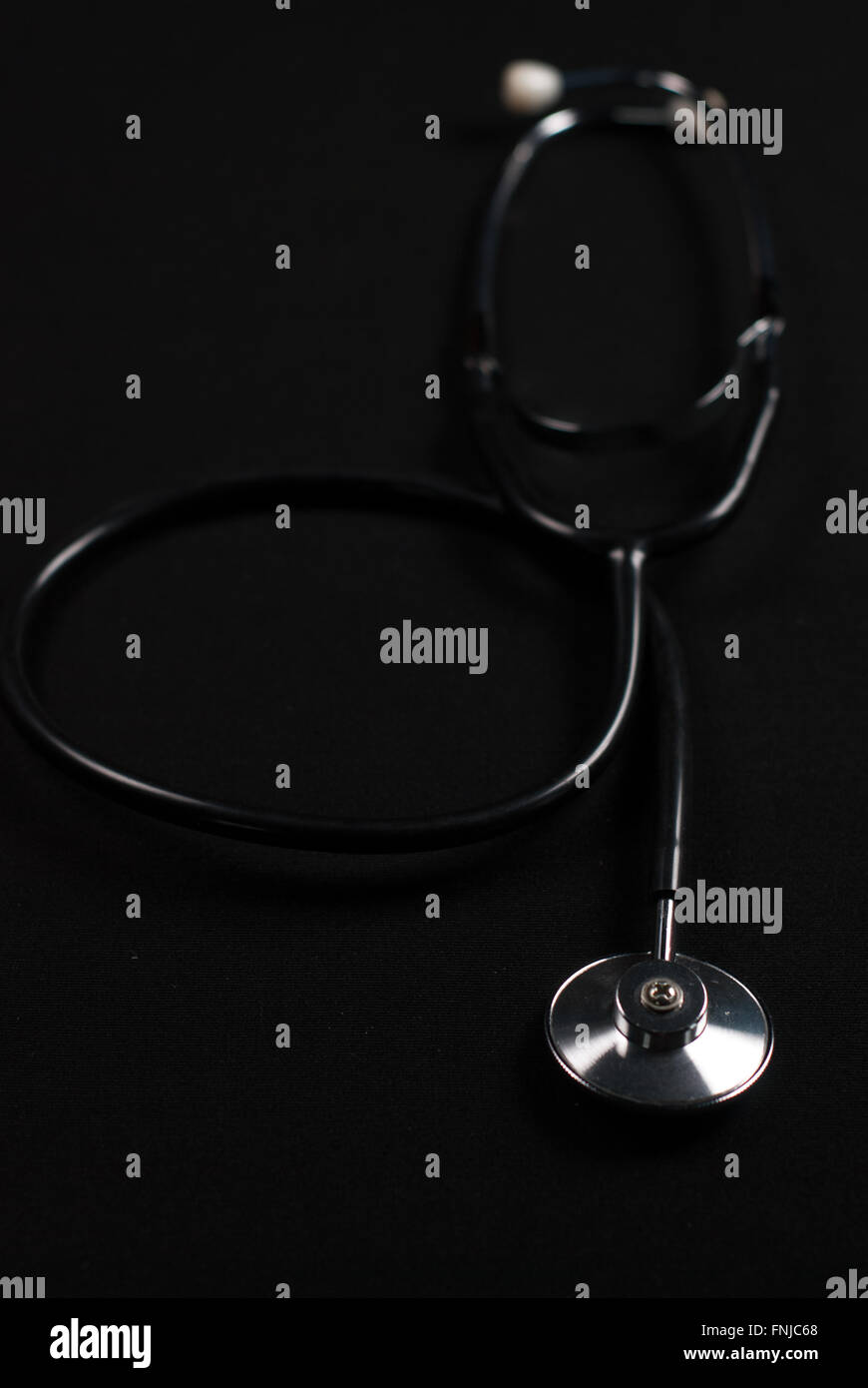 The metal stethoscope on a black background, with reflections of light ...