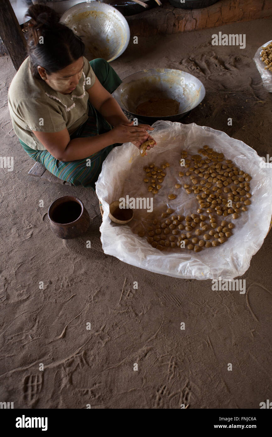 Overhead shot of Burmese woman making palm sugar candy by hand in local ...