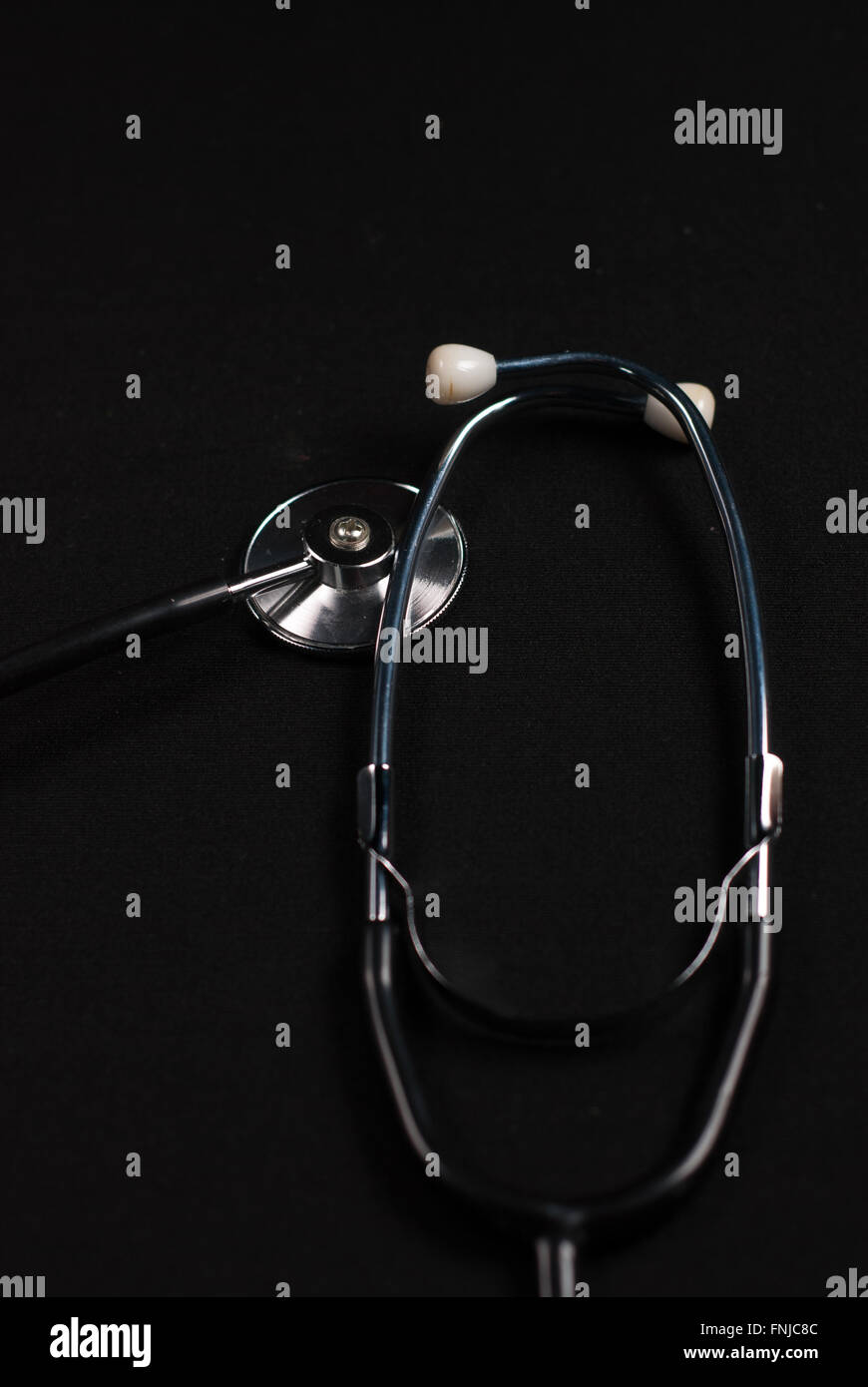 The metal stethoscope on a black background, with reflections of light ...