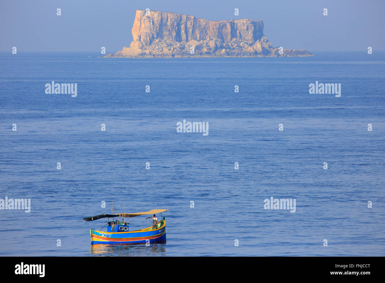 A fisherman in a traditional Maltese fishing boat fishing off the ...