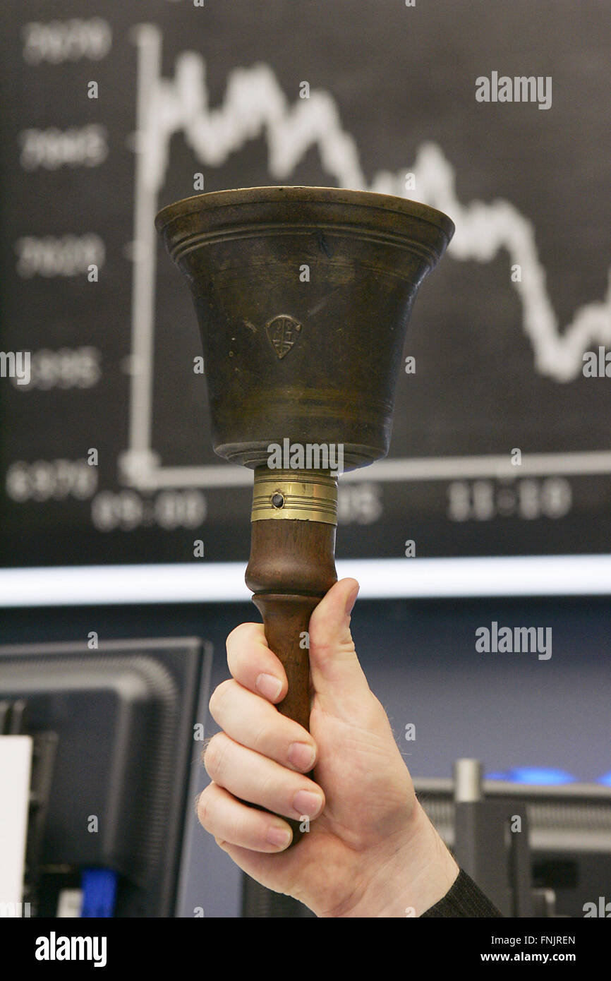 A hand rings the traditional stock exchange bell in a posed scene in ...