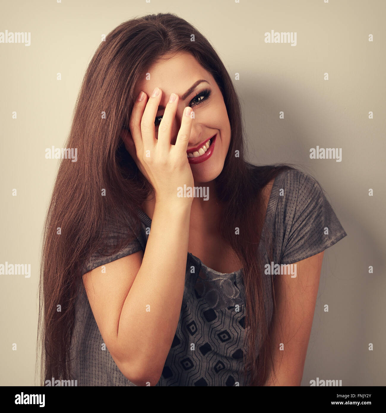 Happy laughing brunette young woman cover the hand her face and ...
