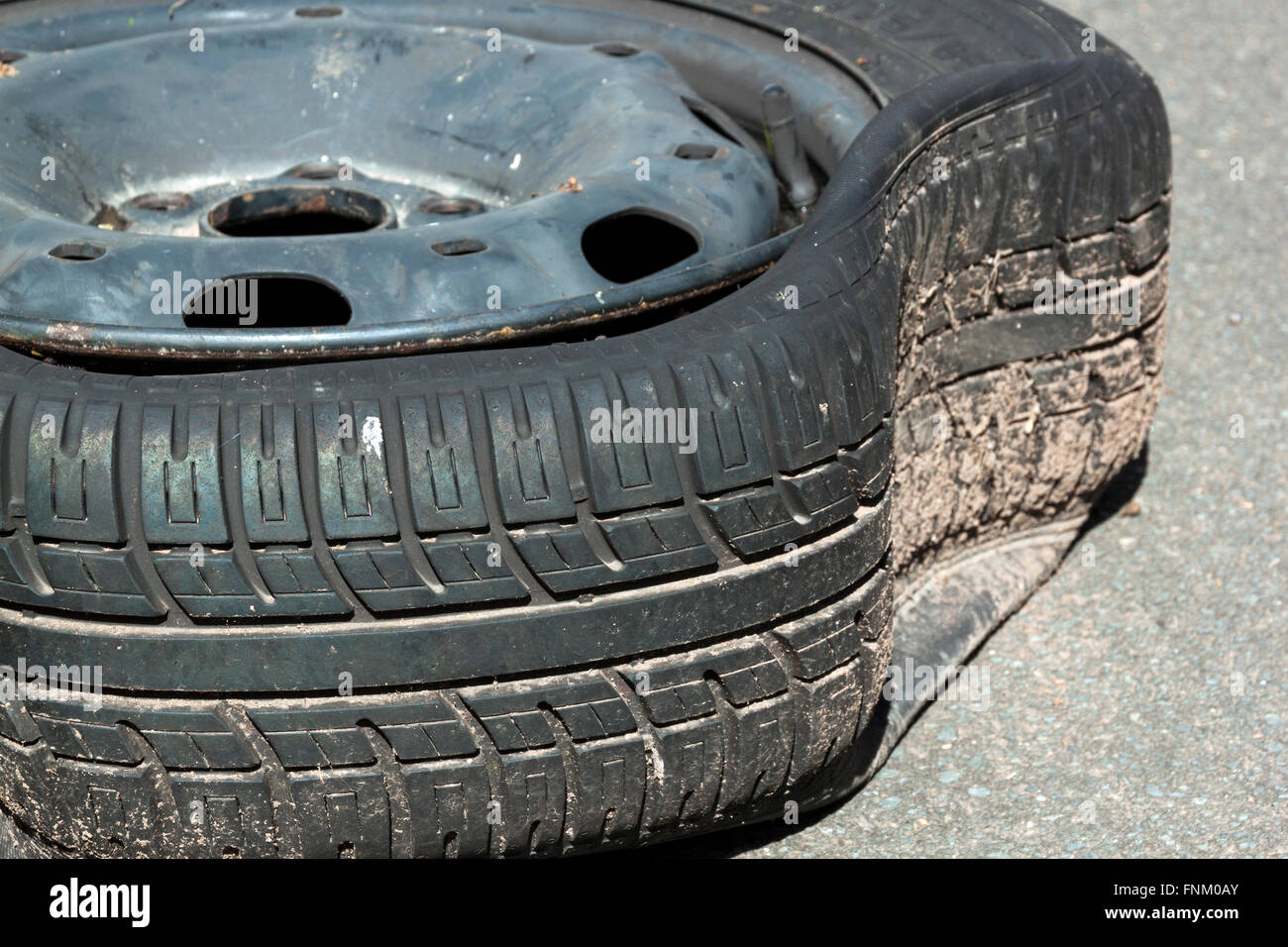 closeup of dirty damaged deflated tire after blowout caused by pot hole ...
