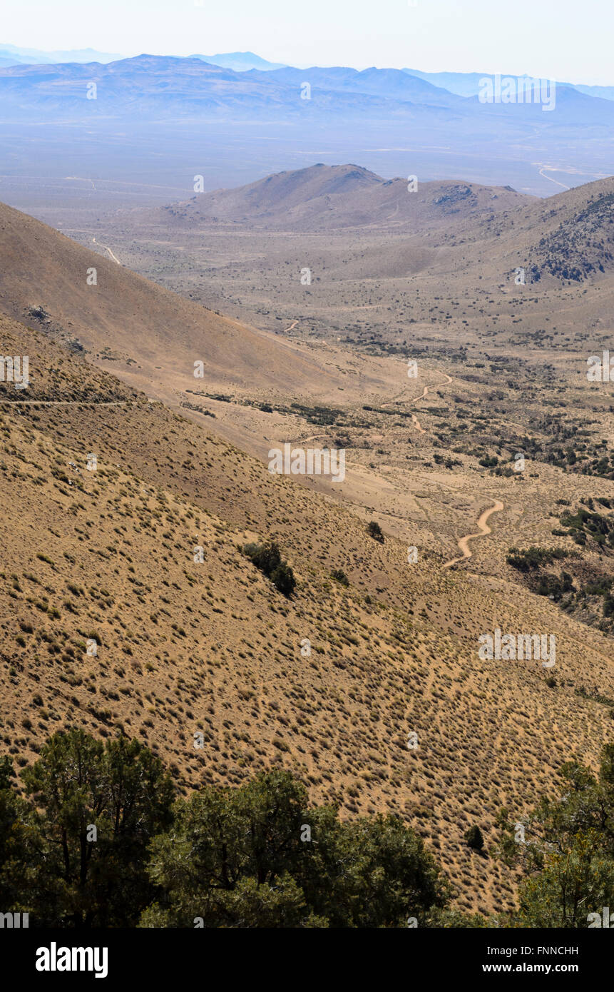 Over looking valley with dirt road running through. Trees, desert, haze on mountains Stock Photo ...