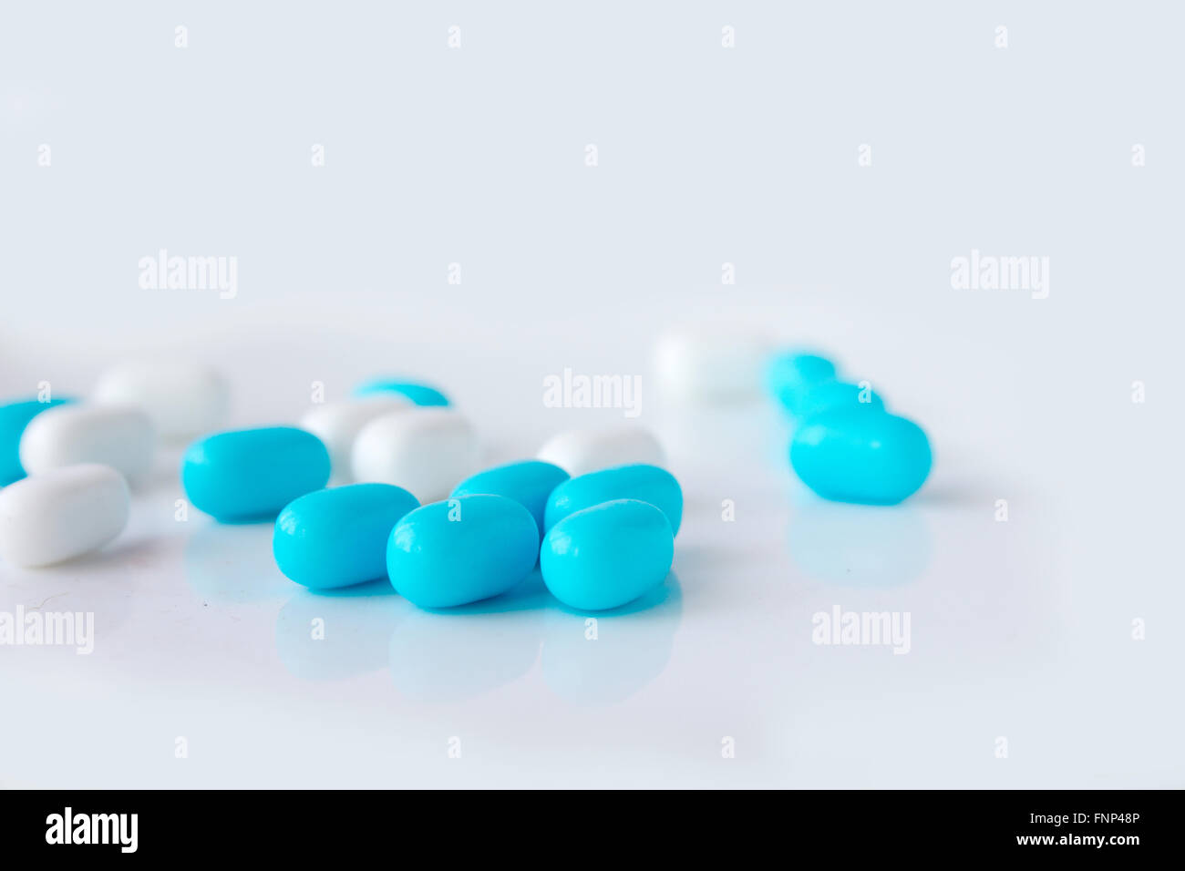 Blue and white pills on white background Stock Photo - Alamy