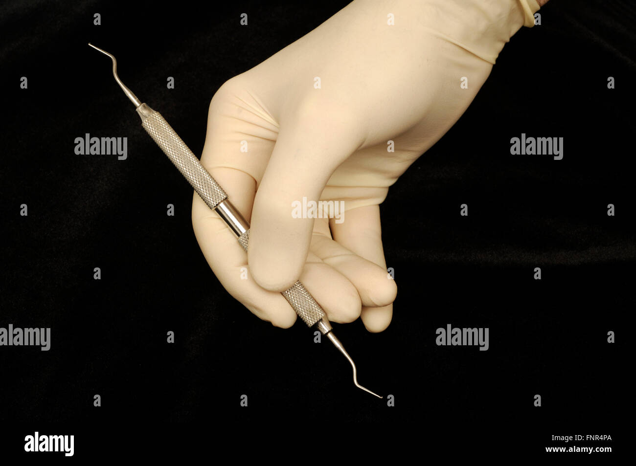 A gloved hand holds a double sided dental probe Stock Photo - Alamy